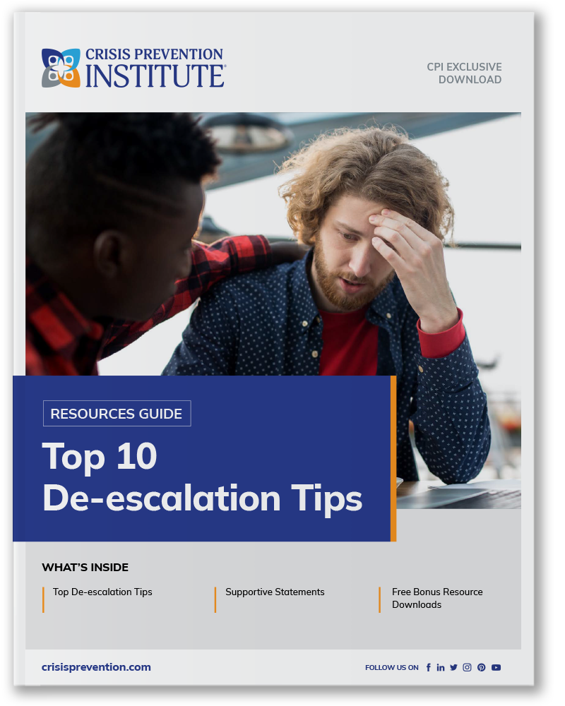 Two men sitting at a table, visibly distressed, with one resting his head in his hands.