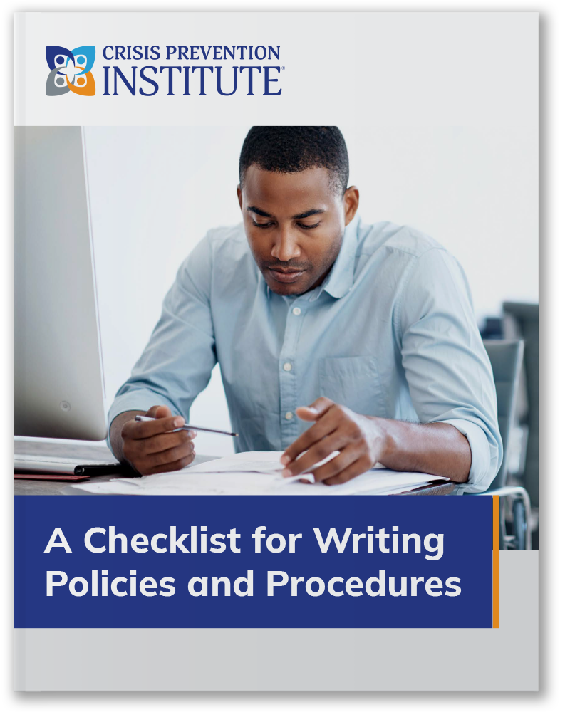 A man at a desk writes with a pen on paper, concentrating on his work.