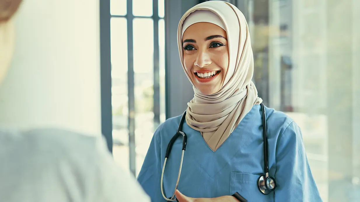 A doctor in Middle Eastern uniform smiling at a patient. The doctor ...